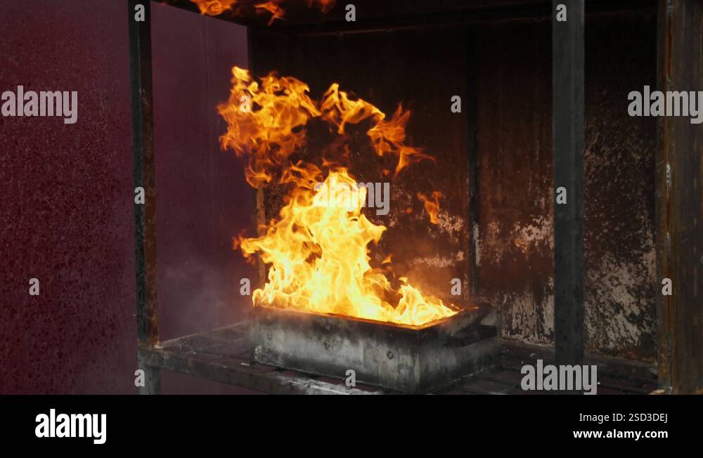 Shining orange and red fire with rising tongues over a black tub in ...