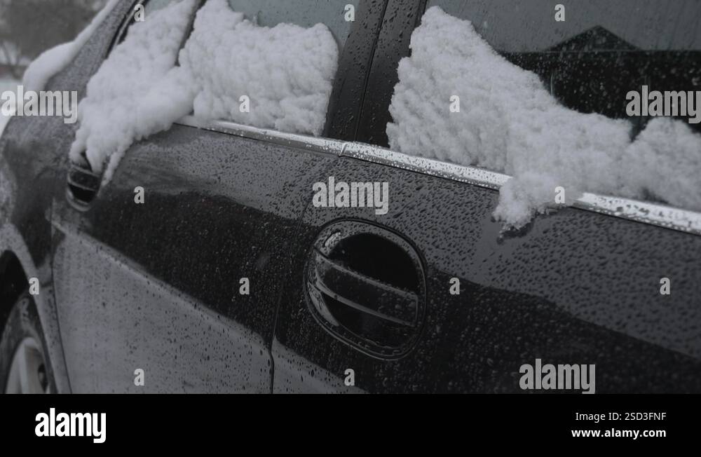 Snow lies on a car's side windows during snowfall in winter daytime ...