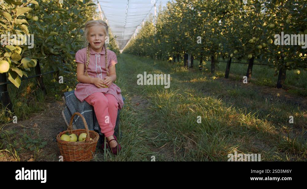 Happy little girl is lifting an apple above her head and throwing it ...