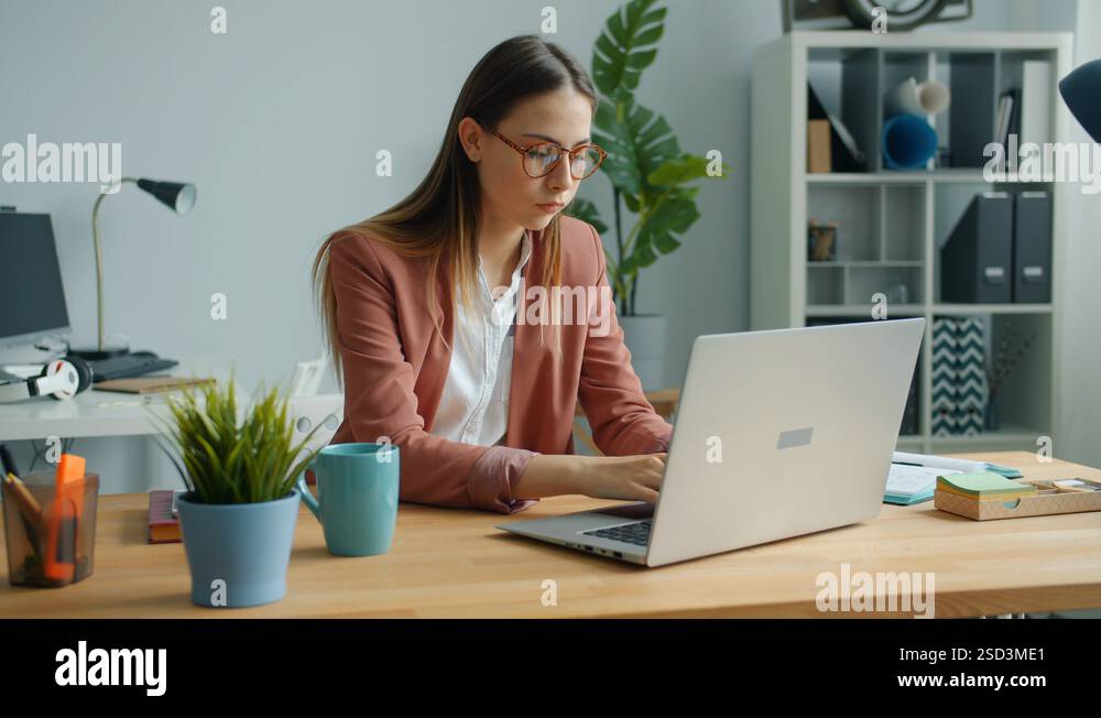 Stressed office worker typing on laptop then taking off glasses feeling ...