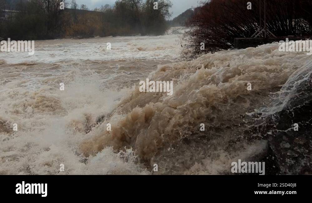 Close up tilt down low angle flooding turbulent water flowing over ...