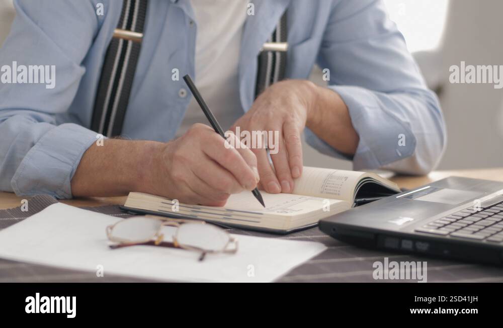 Close up of male hands holding pen to take notes in notebook ...