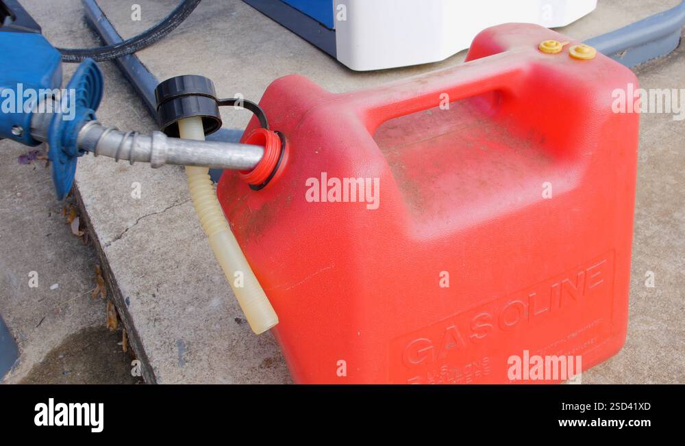 Refueling gas pump nozzle and red fuel container at petrol filling ...