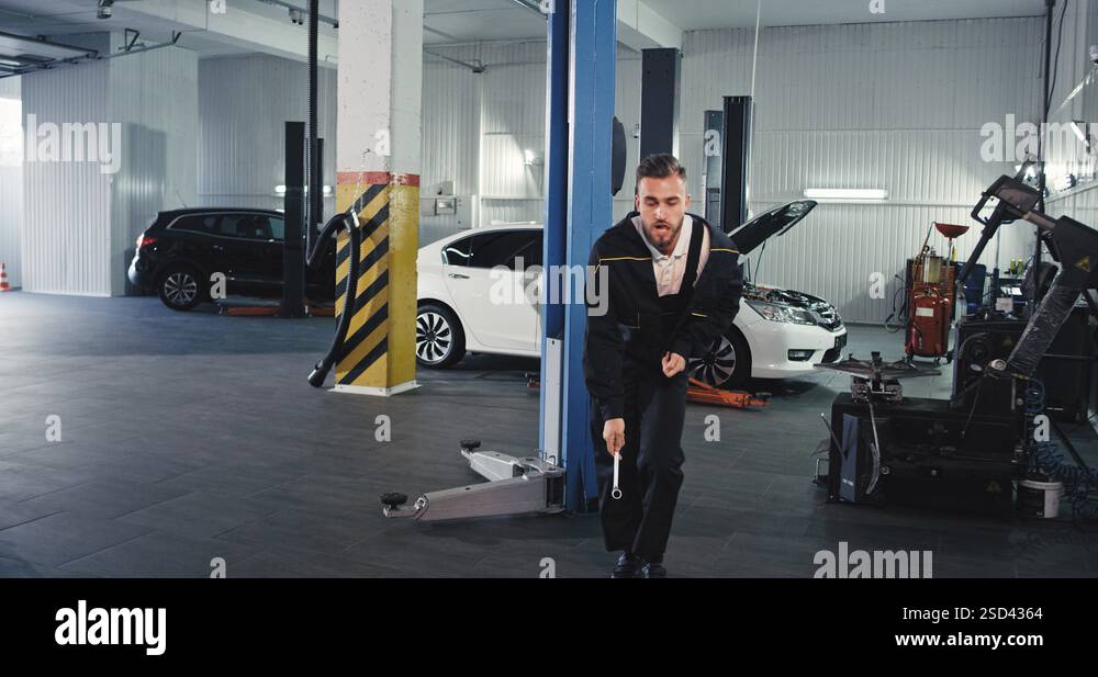 Mechanic man in a uniform dancing funny in a large service auto center ...
