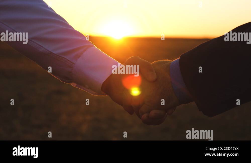 handshake at sunset . man in blue shirt and jacket and man in white ...
