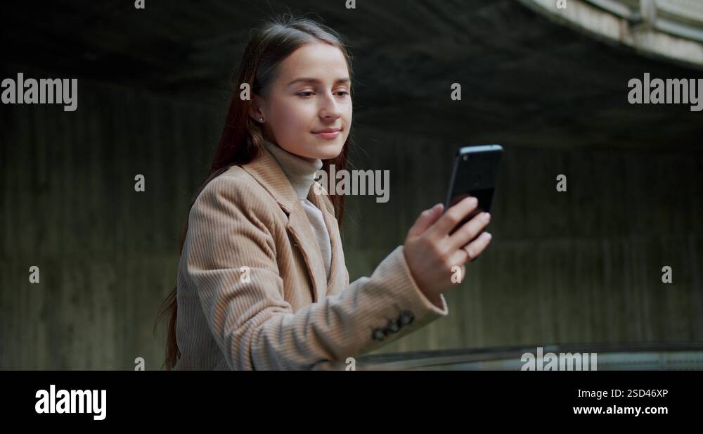 Portrait of thoughtful girl dreamily smiling holding black smartphone ...
