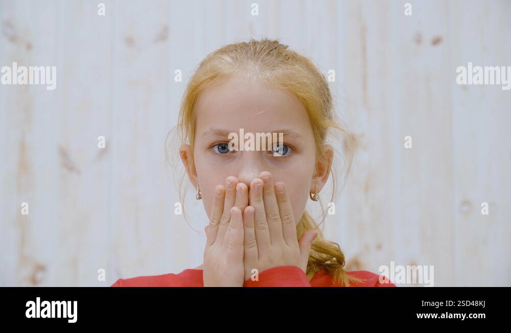 Portrait scared girl teenager closing face with hands in light studio ...