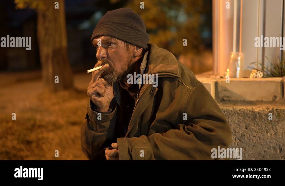 Homeless sick man smoking cigarette on the street at night Stock Video ...