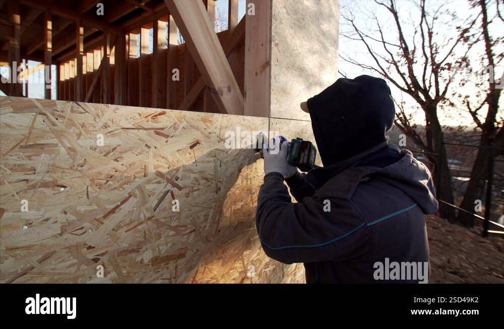 Builder is cutting a plywood with small electric circular saw. House ...
