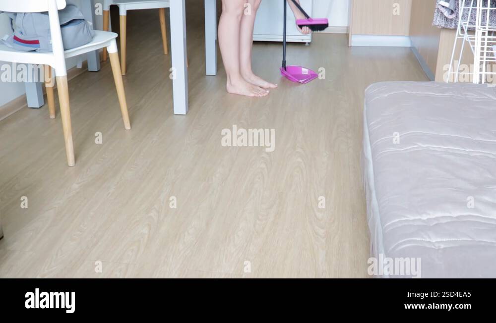 Woman cleaning sweeping the kitchen floor with a brush and dustpan ...
