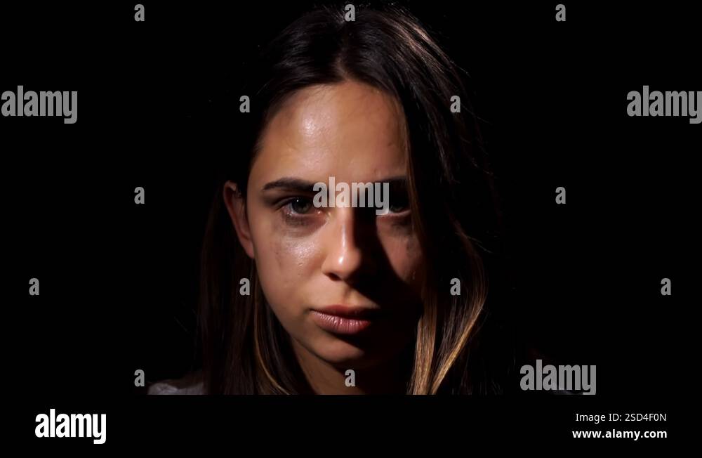 A tearful and frightened sad girl looking in the camera on black ...