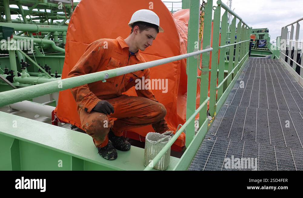 sailor in orange uniform paints railing sitting on haunches Stock Video ...