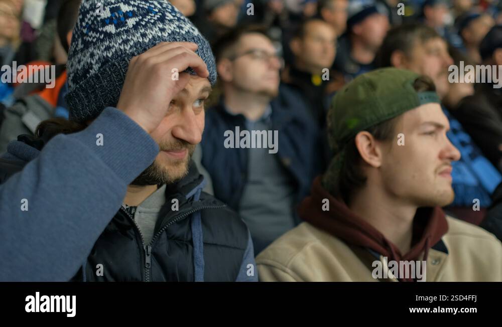 Portrait tired hockey fan boring game closeup in crowd stadium rub face ...