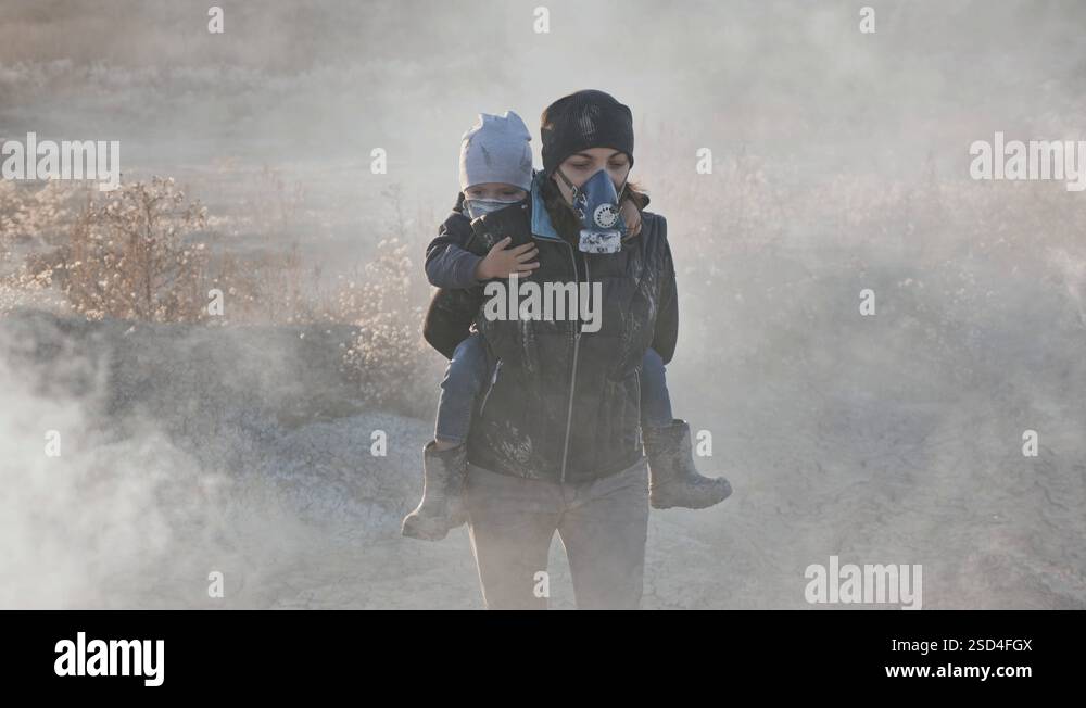 A survivor mother carring her son in gas mask going through clouds of ...