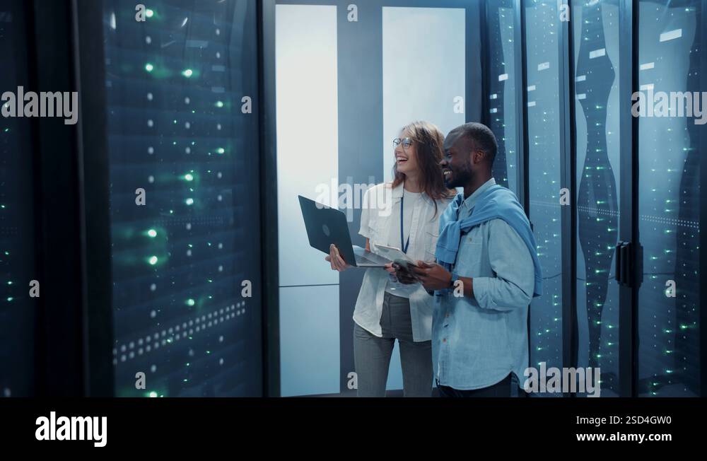 Cheerful multi-race data center team having fun while working in server ...