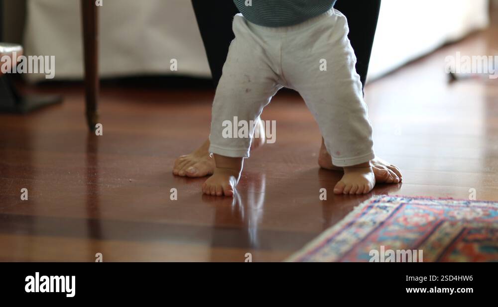 Baby feet learning walk and stand. Mother helping toddler learn to walk ...