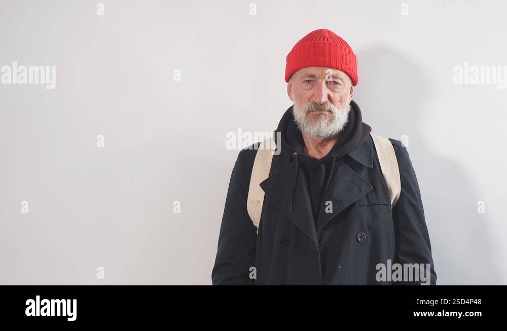 Poor old-aged bum in red hat and street wear holding cardboard sign ...