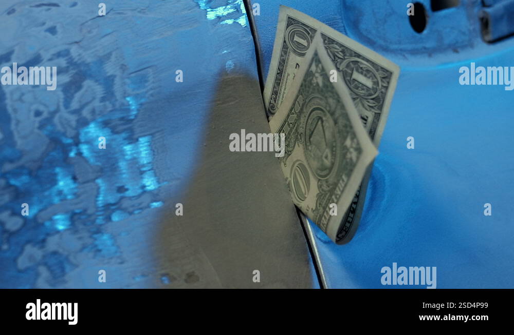 One dollar bill stuck in the gap of an unrepaired car. Close-up. The ...