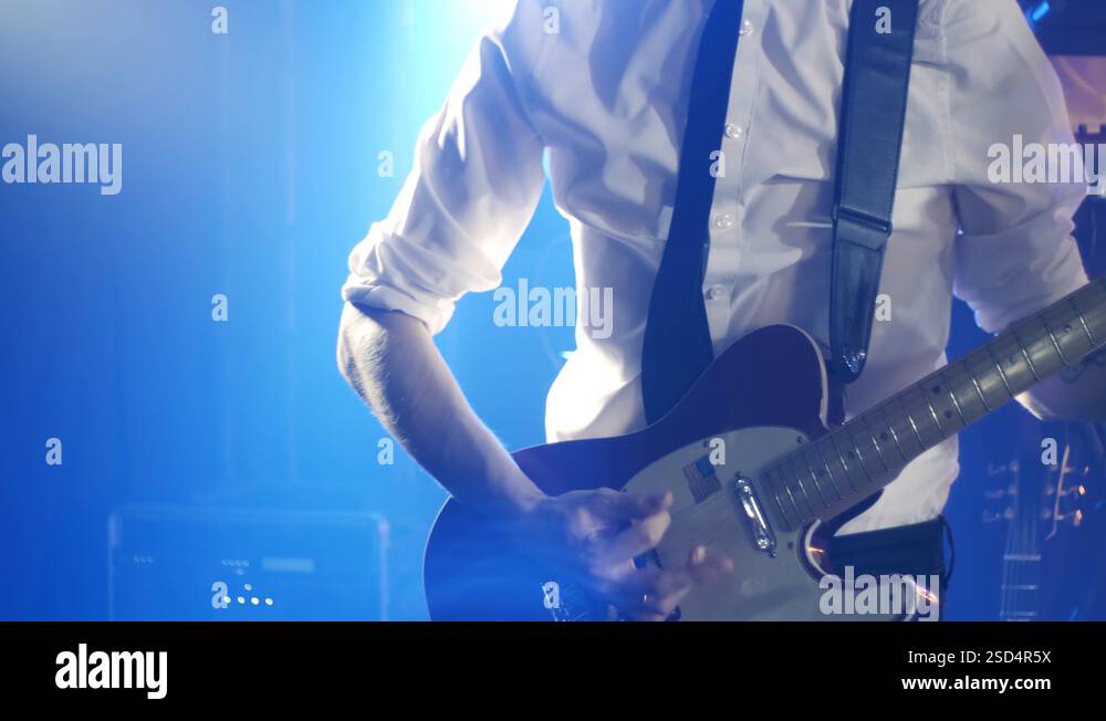 Guitarist in a white shirt and black tie plays rythm guitar and dances ...