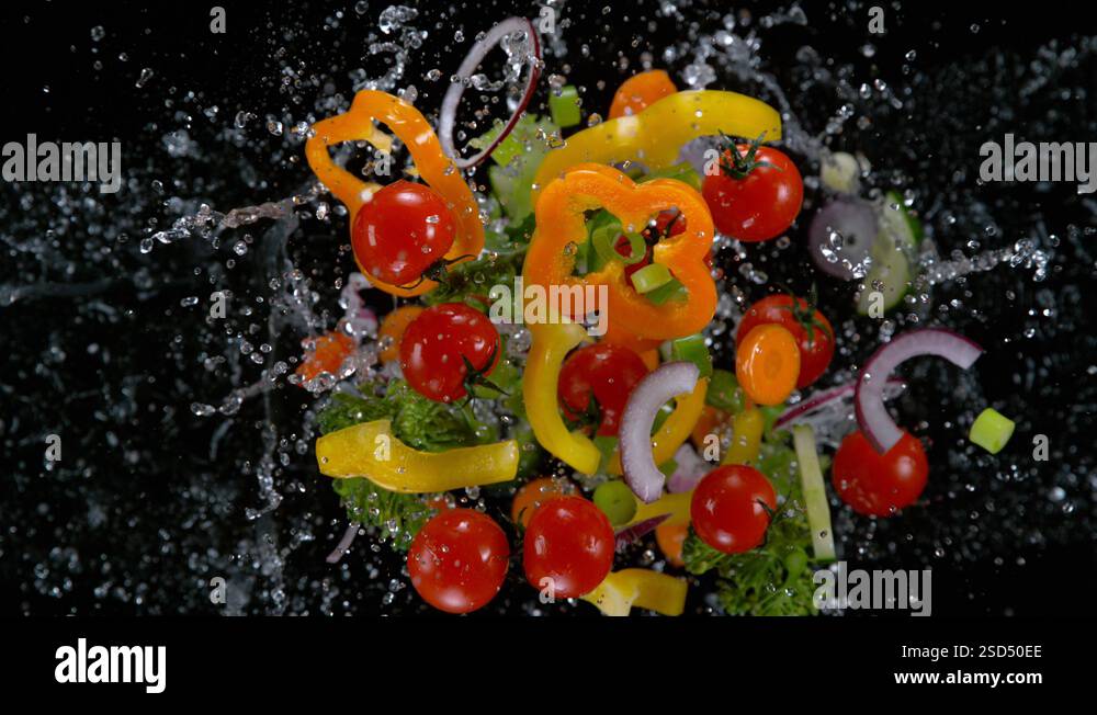 Fresh vegetables with water droplets exploding on black background ...