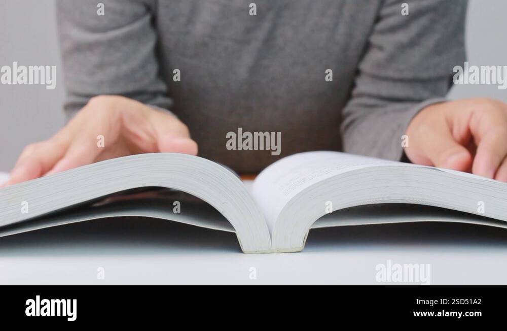 A student quickly turning the pages of a book and closes the cover ...