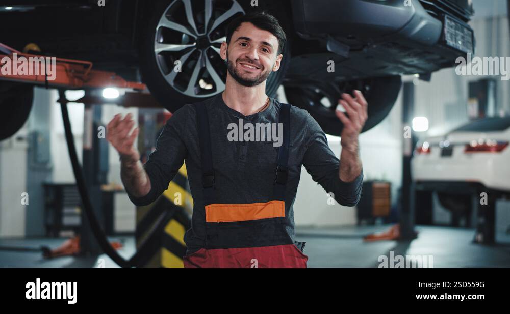 Charismatic mechanic guy in the uniform in front of the camera looking ...