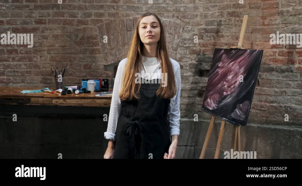 Portrait of talented pretty female artist with brush and her canvas on ...