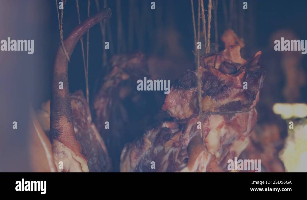 Bacon hanging and drying in smokehouse on traditional way on blue smoke ...