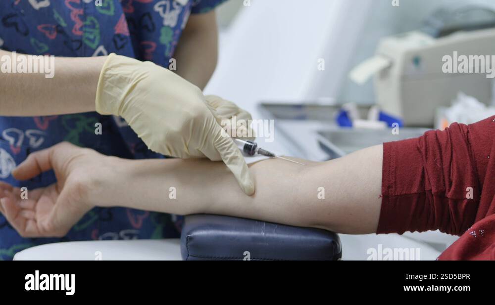 Patient pumps blood by hand before taking a blood test. A nurse wipes ...