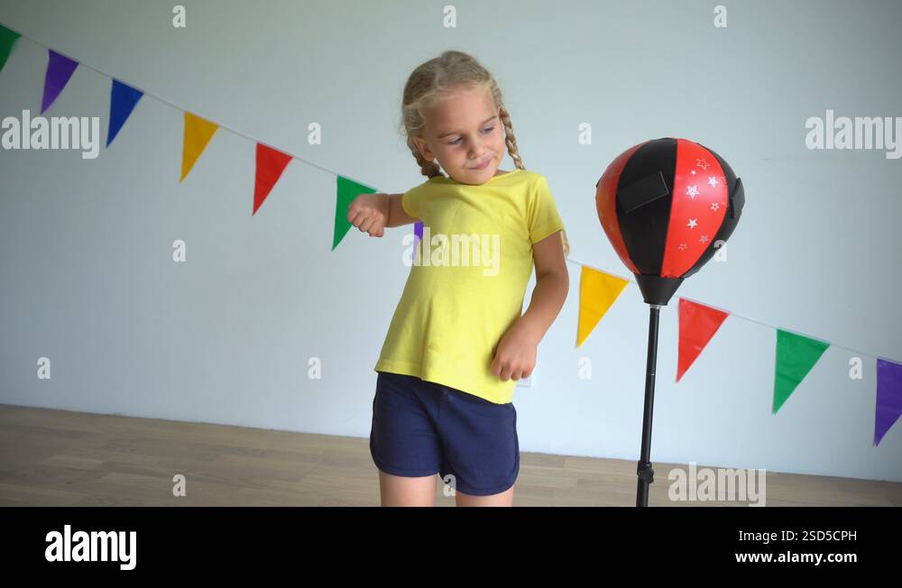 caucasian child hitting punching bag. Active playful girl have fun at ...