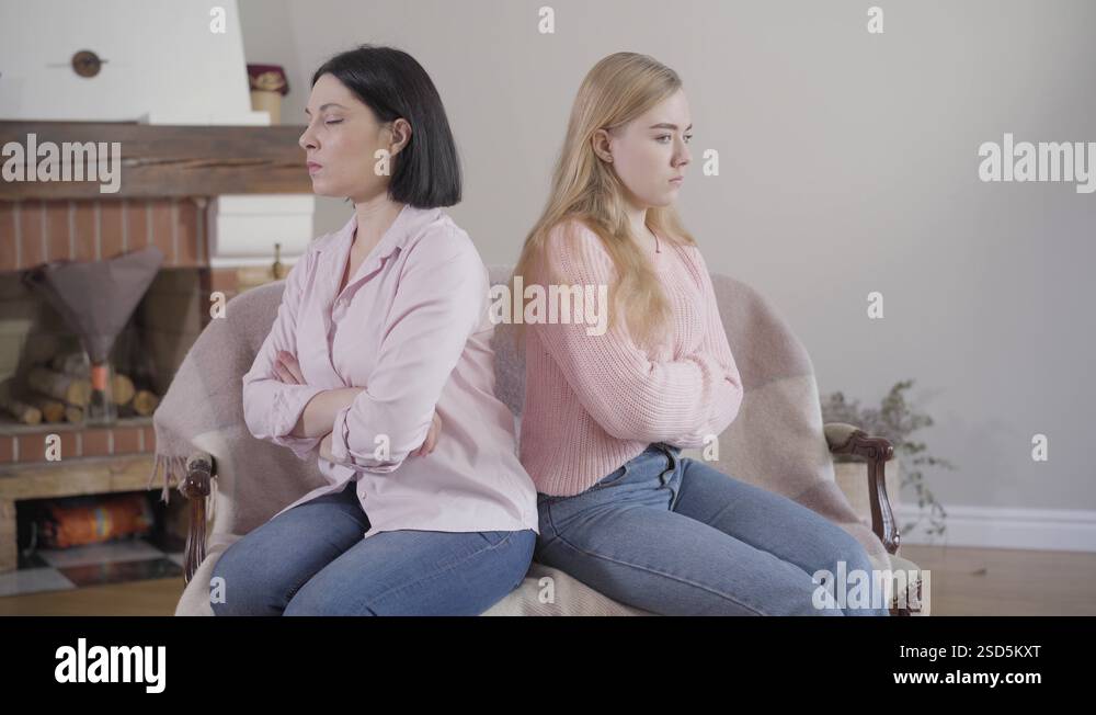 Side view of adult Caucasian brunette woman and teen girl sitting back ...