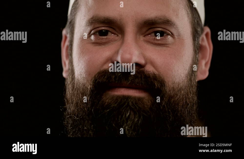 Man with beard in studio on black background puts on cook uniform ...