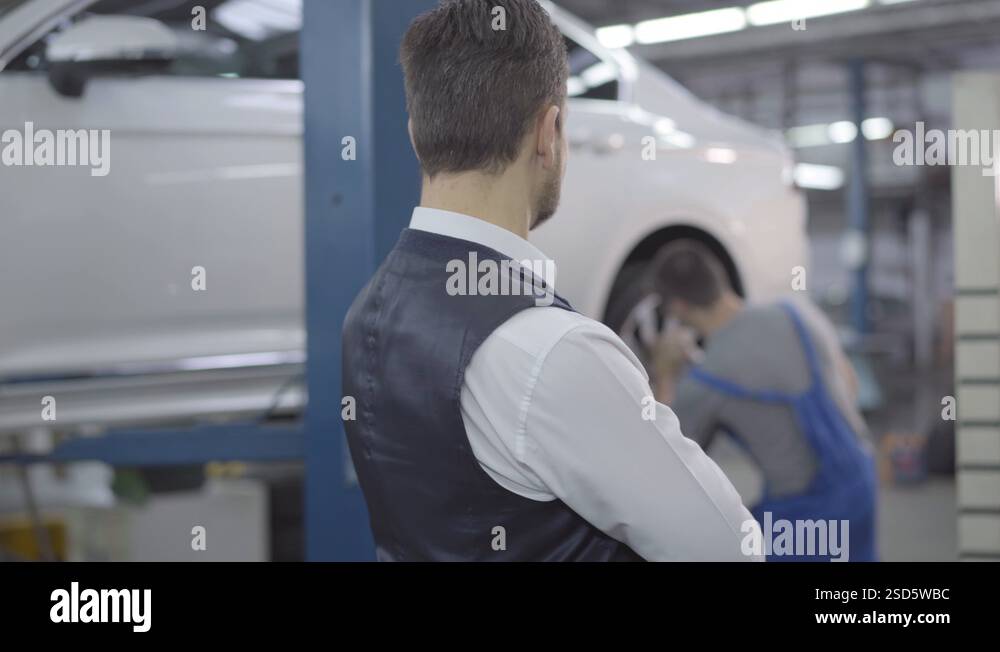 Back view of adult Caucasian man looking back at worker tightening ...