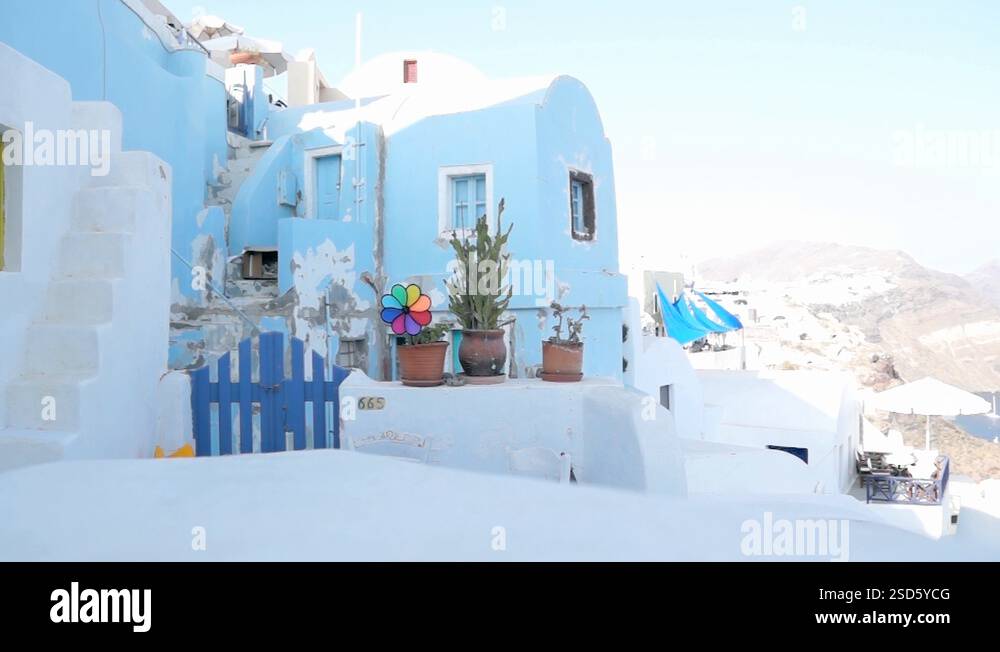 Colorful windmill moving in the front of a typical Greek building, Oia ...