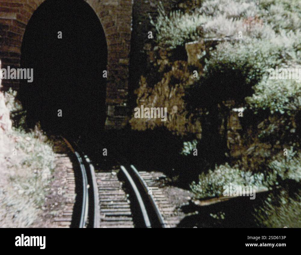 1950s: Train travelling down tracks comes out of tunnel. Train ...