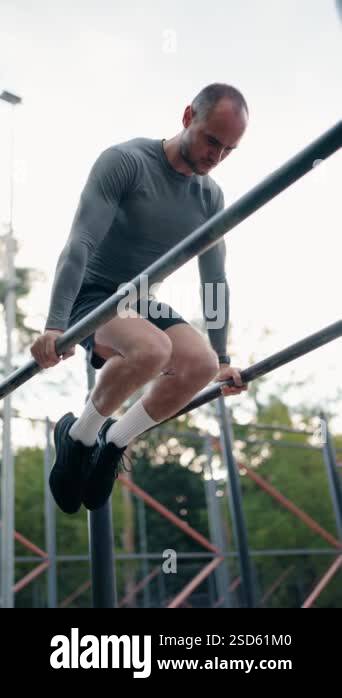 A determined man exercises on parallel bars at an outdoor gym ...