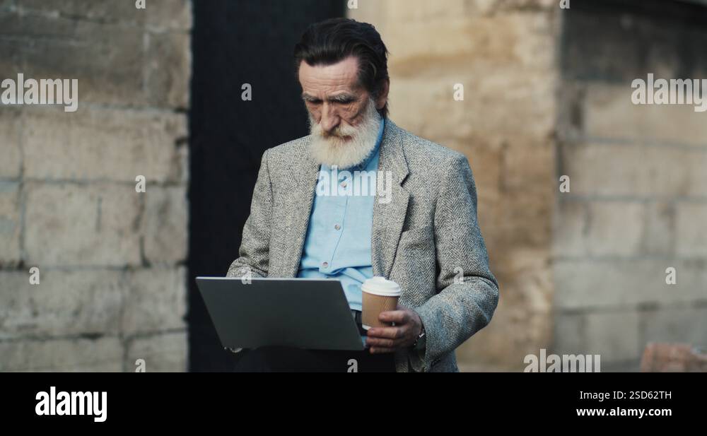 Old Caucasian man with long grey beard typing on the keyboard of the ...