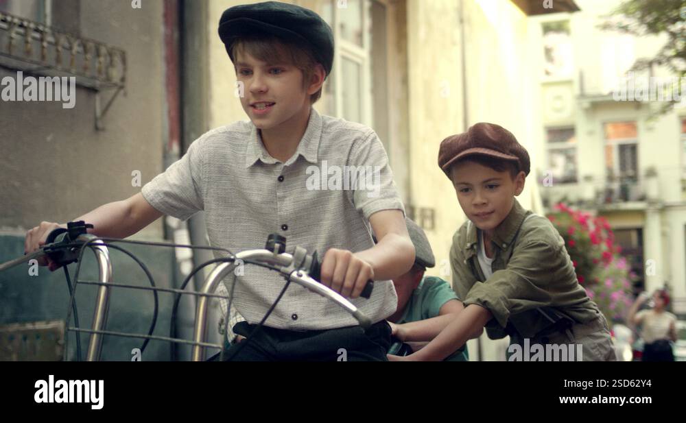 Caucasian teen boy in a hat riding a retro moped and his small friends ...