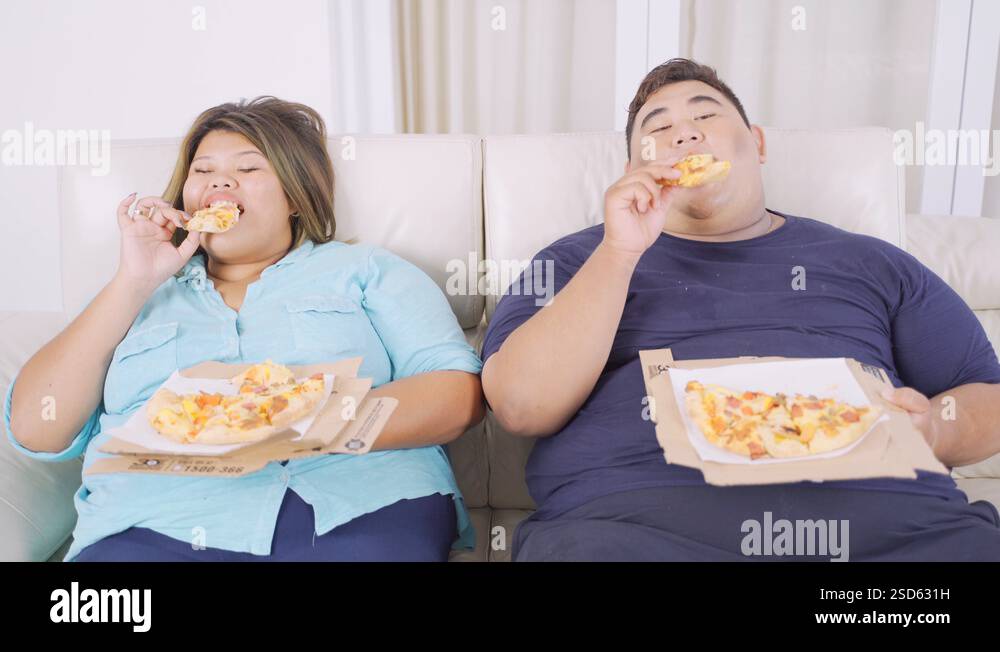 Overweight couple eating pizza together at home Stock Video Footage - Alamy