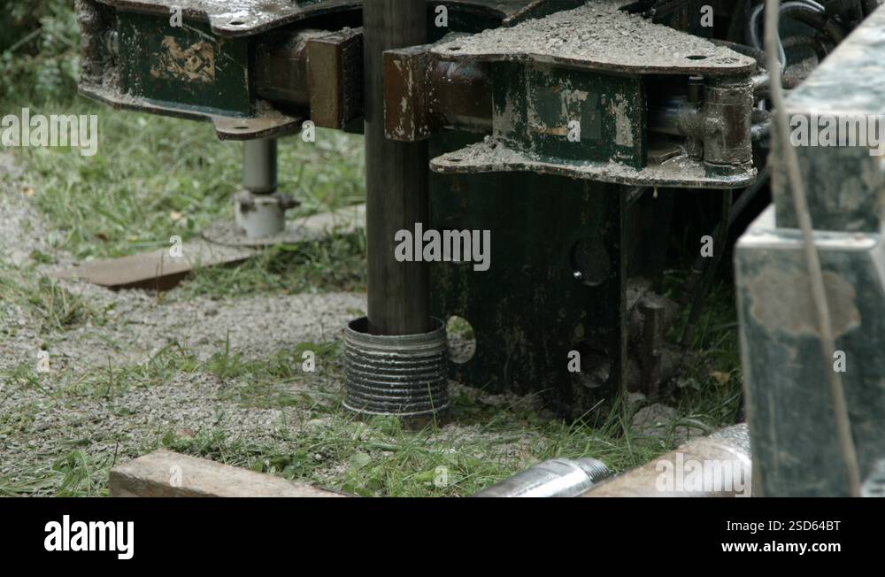 Rotary drill rig pulling out drilling pipes from groundwater borehole ...