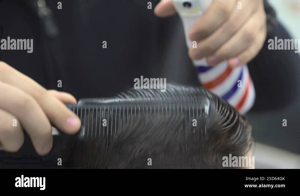 Haircut in a Barbershop. Barber combs the client's hair and sprinkles ...