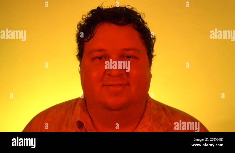 Portrait shot with red lighting: Fat man standing isolated on yellow ...