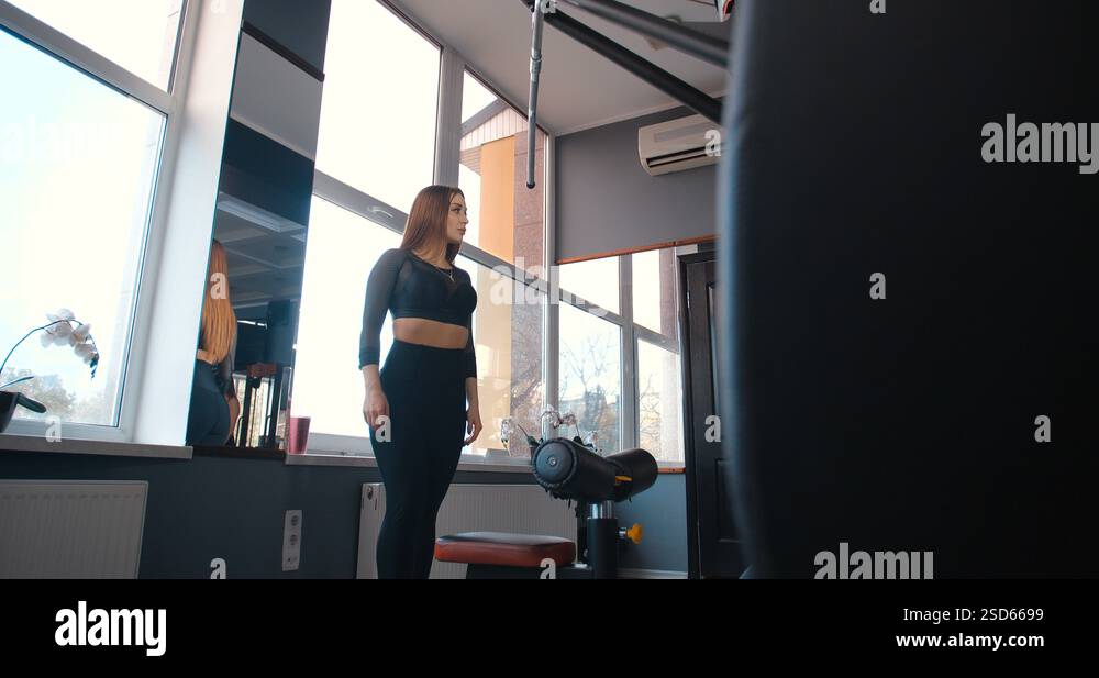 Female athlete in the gym. Attractive girl with red hair performing ...