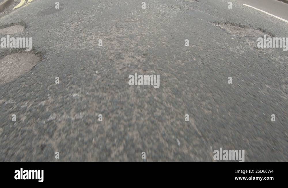 Vehicle driving over a bumpy, damaged road covered in Potholes in the ...