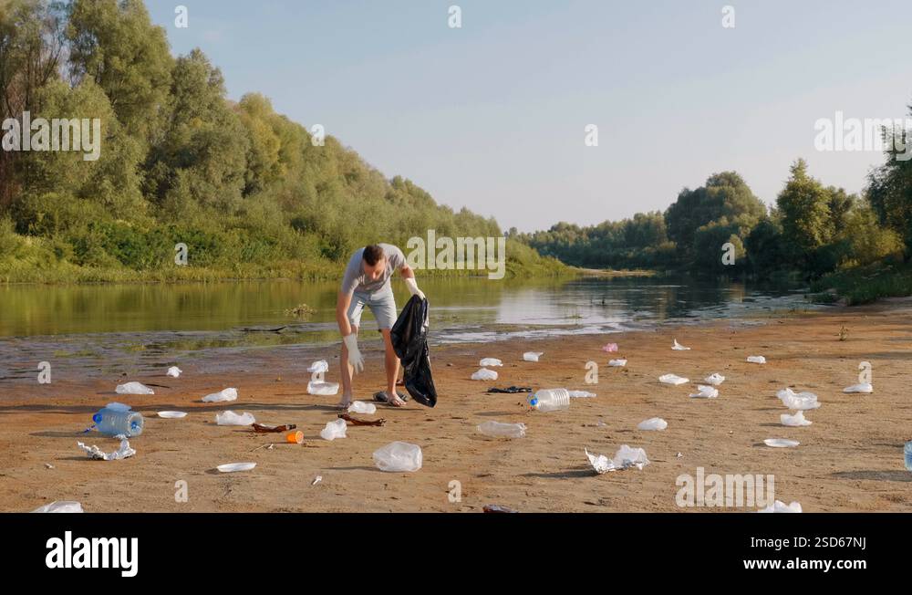 Angry man collects plastic trash on the banks of polluted river, drops ...