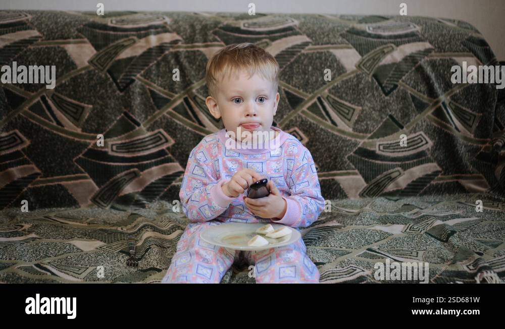 Small boy is watching TV, push button on remote control, emotions from ...