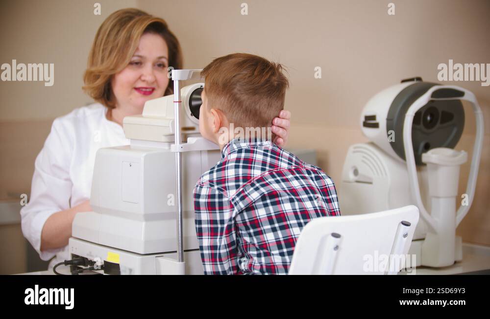 Boy having a treatment in eye clinic - a woman doctor checking little ...