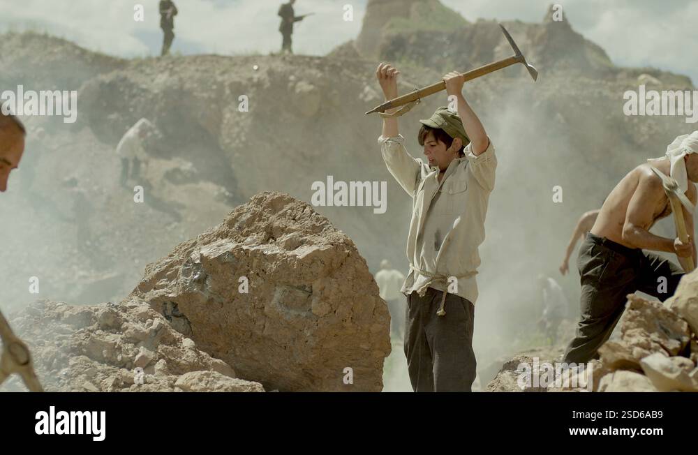 Young miner boy is working in a quarry . Many workers are mining with ...