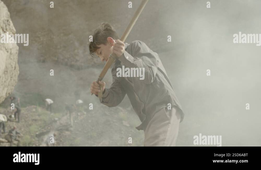 Young miner boy is working in a quarry . Many workers are mining with ...