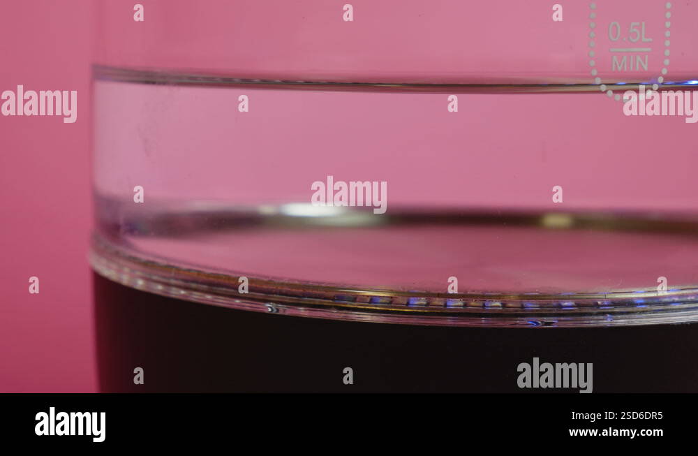 Boiling water in a glass teapot on a pink background. Close-up Stock ...
